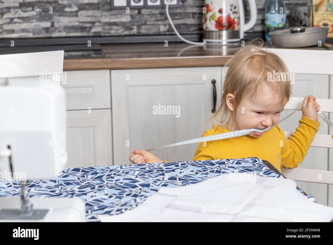 Cute little boy is playing with tailor’s tape measure sitting at a ...