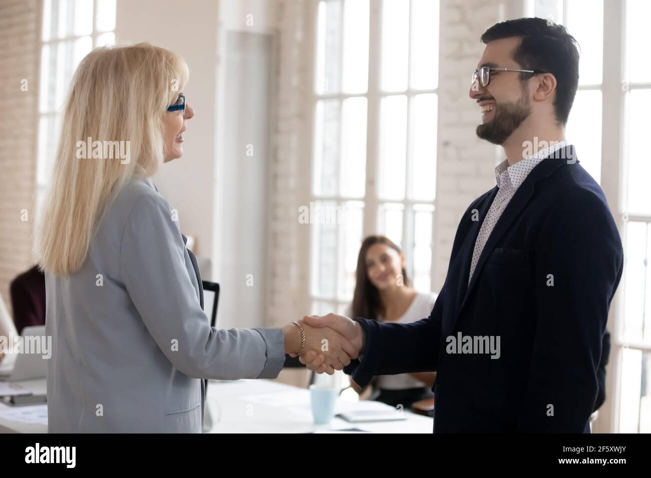 Male boss shake hand of female employee congratulate with promotion ...