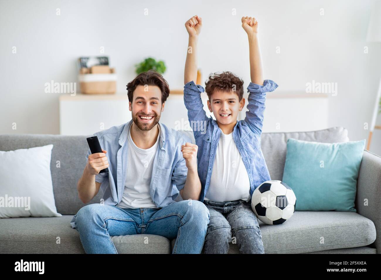 Amazing game. Overjoyed dad and son cheering football at home ...