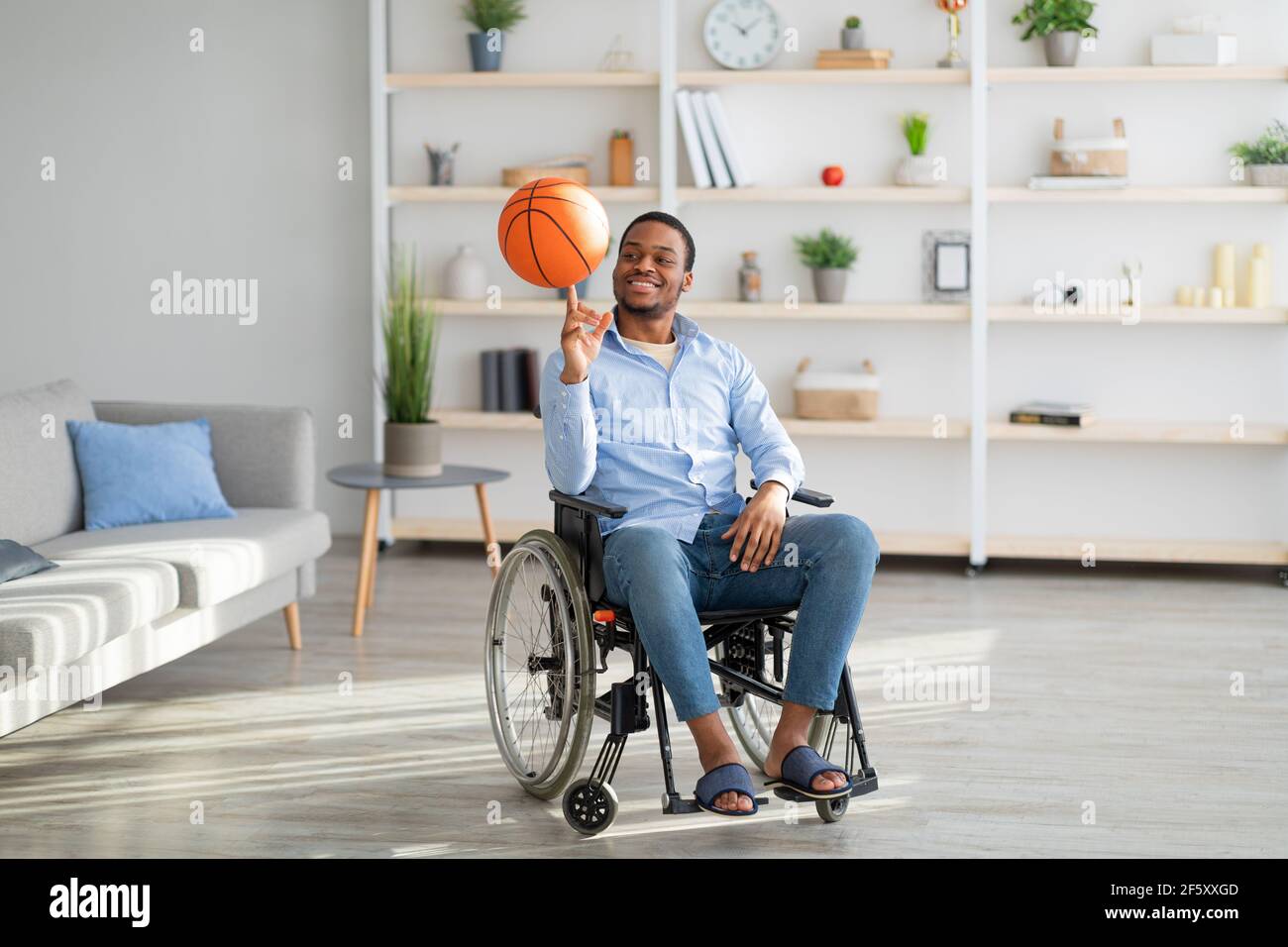 Happy disabled black guy spinning basketball on his finger, sitting in ...