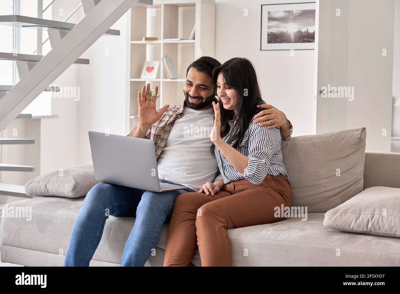 Happy indian couple using laptop waving on video call virtual meeting ...