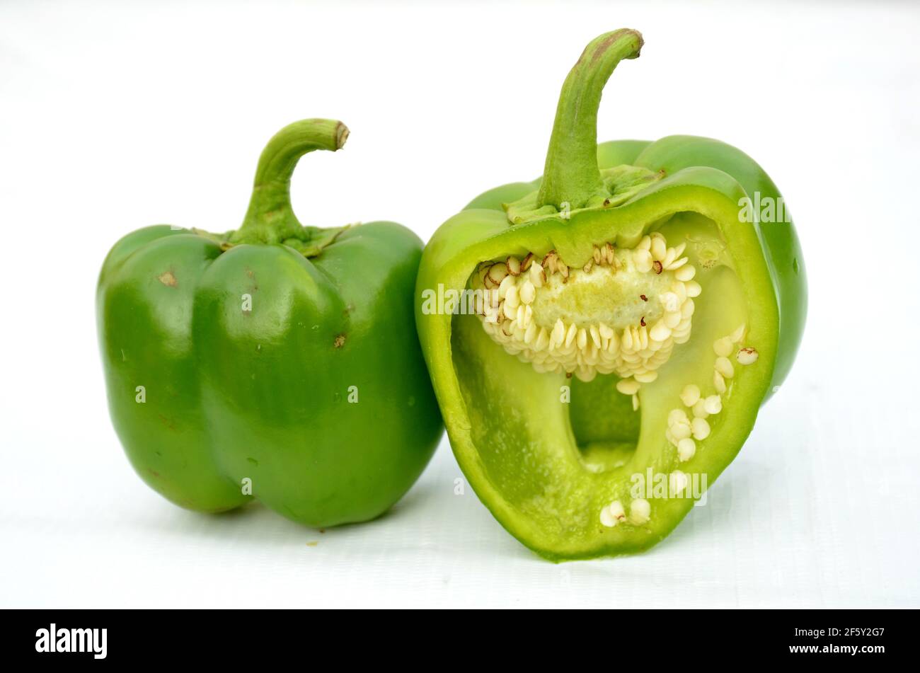 A ripe green cut capsicum or bell pepper isolated on white background ...