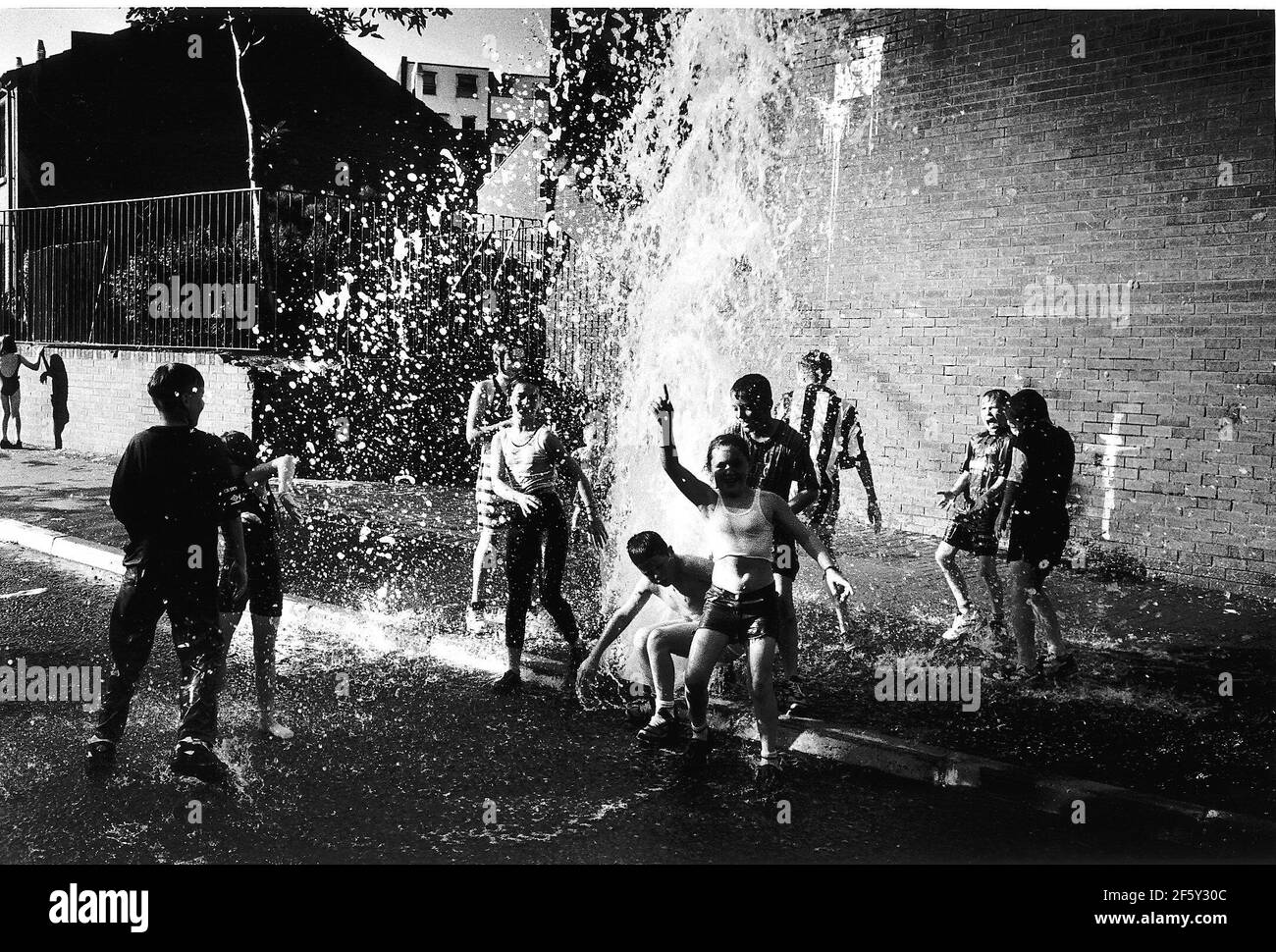 children play in a burst water pipe in the street Belfast Northern ...