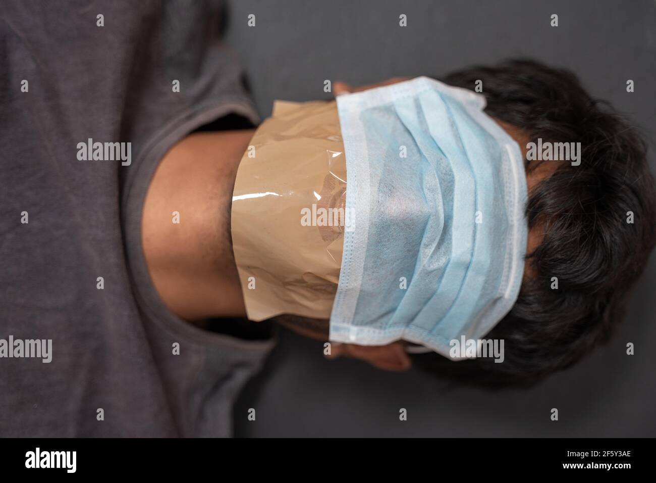 A portrait of a male covering his face with a medical face mask and ...