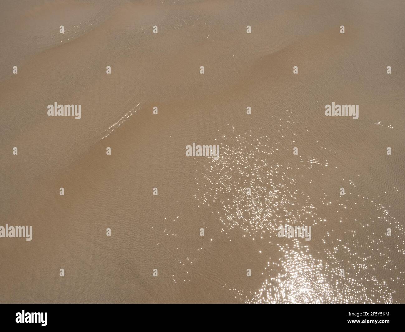 Light reflections off water covered sand on the beach at Norman Bay ...