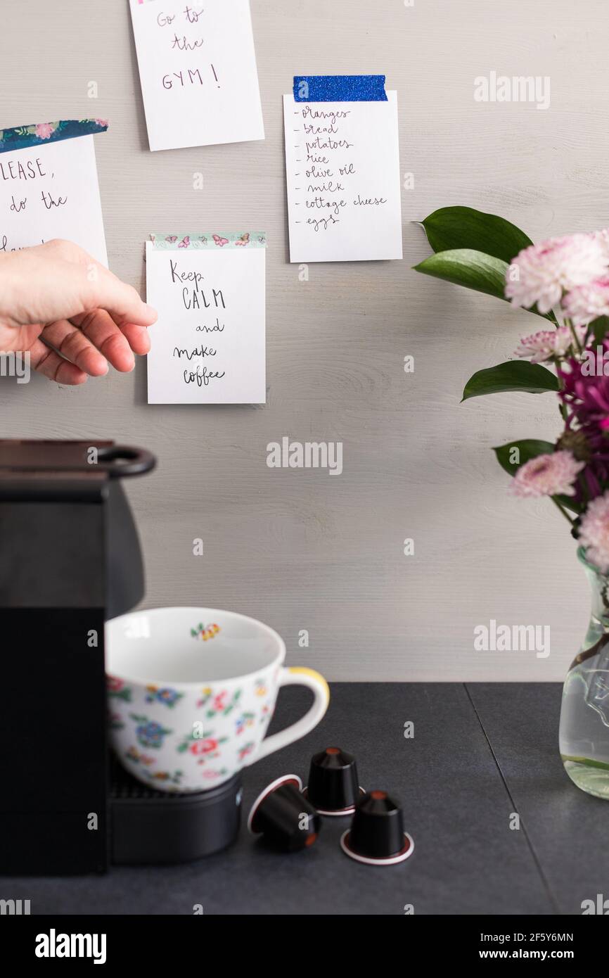 Woman hand holding the coffee reminder note from a grey wooden wall ...