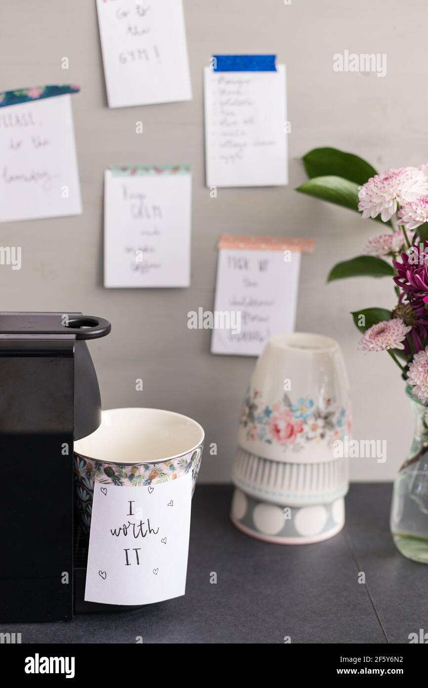 A sticky note posted in a cup of coffee on a black table and more ...