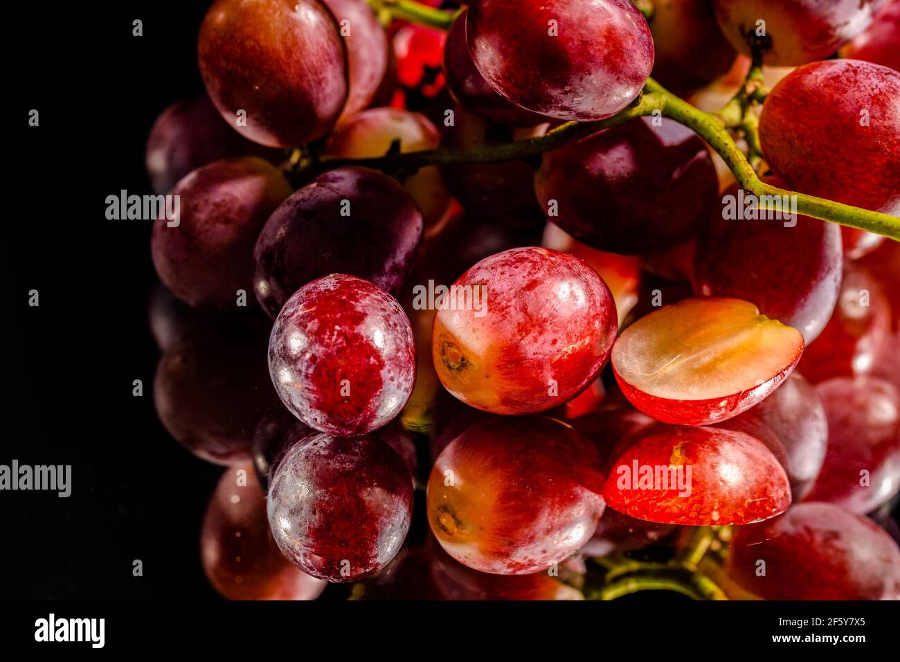 The grapes were cut in half on the mirror with a black background Stock ...