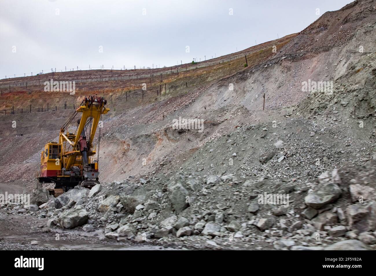 Rudny, Kazakhstan: Open-pit mining iron ore. Yellow excavator on quarry ...