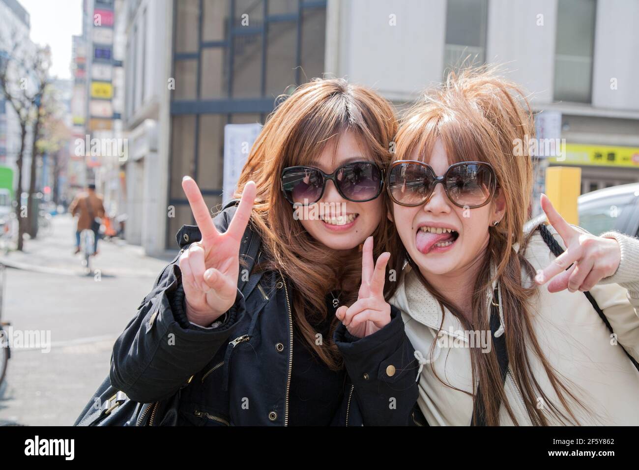 Two Pretty Japanese Girls Posing With V Sign And Poking Tongue Tokyo