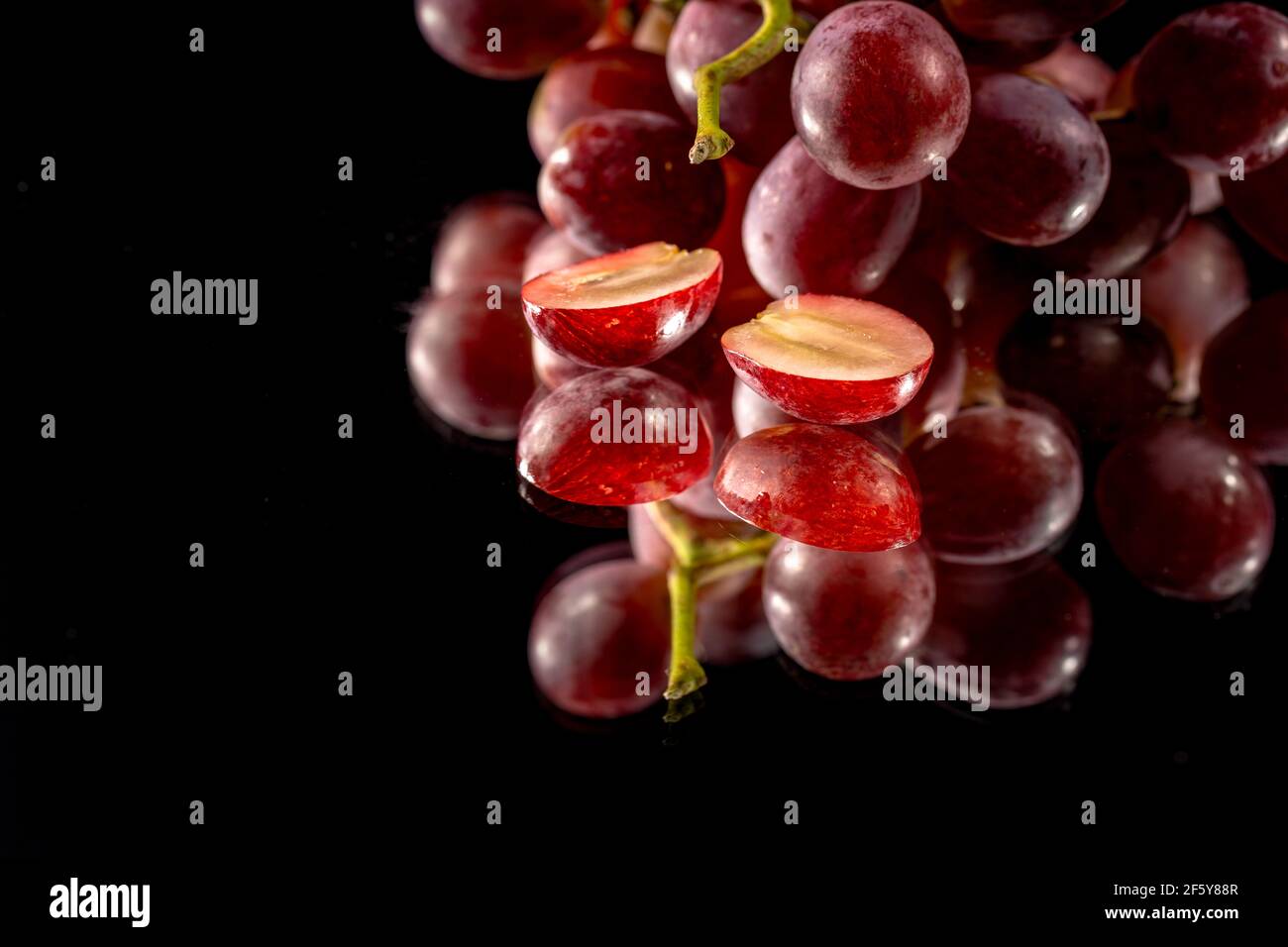 The grapes were cut in half on the mirror with a black background Stock ...