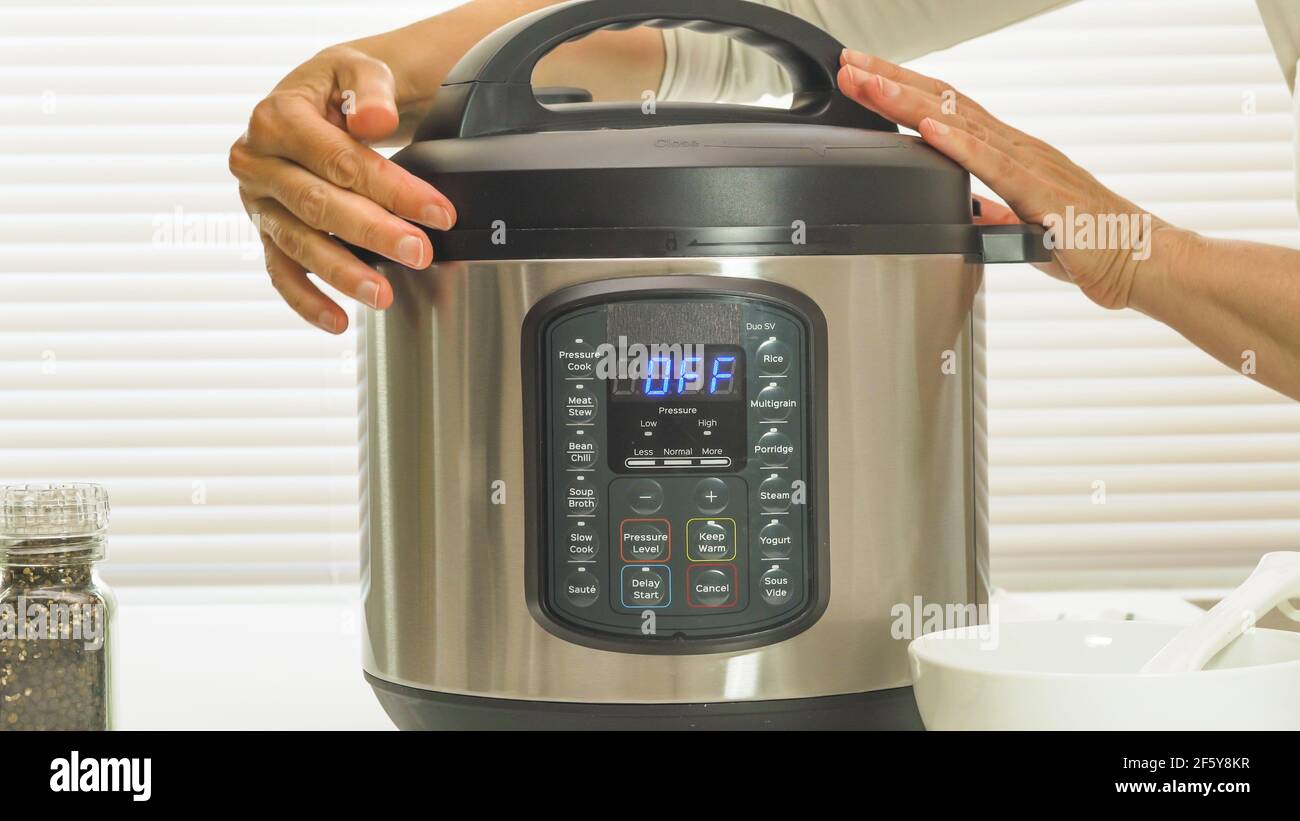 Multi cooker close up on kitchen table. Woman lifting the lid Stock ...