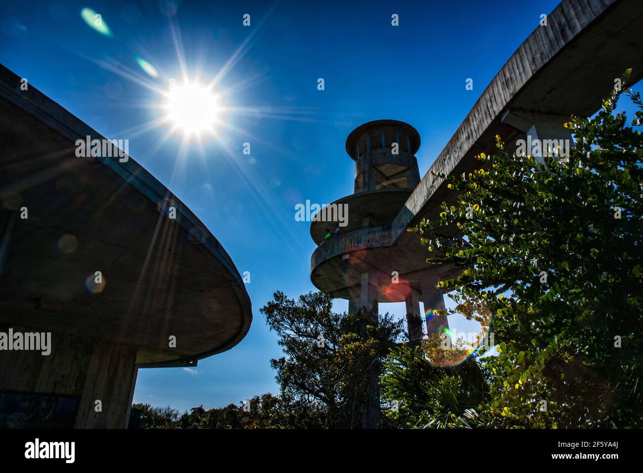 The sun forms a star flare by the shilhouetted observation tower at ...