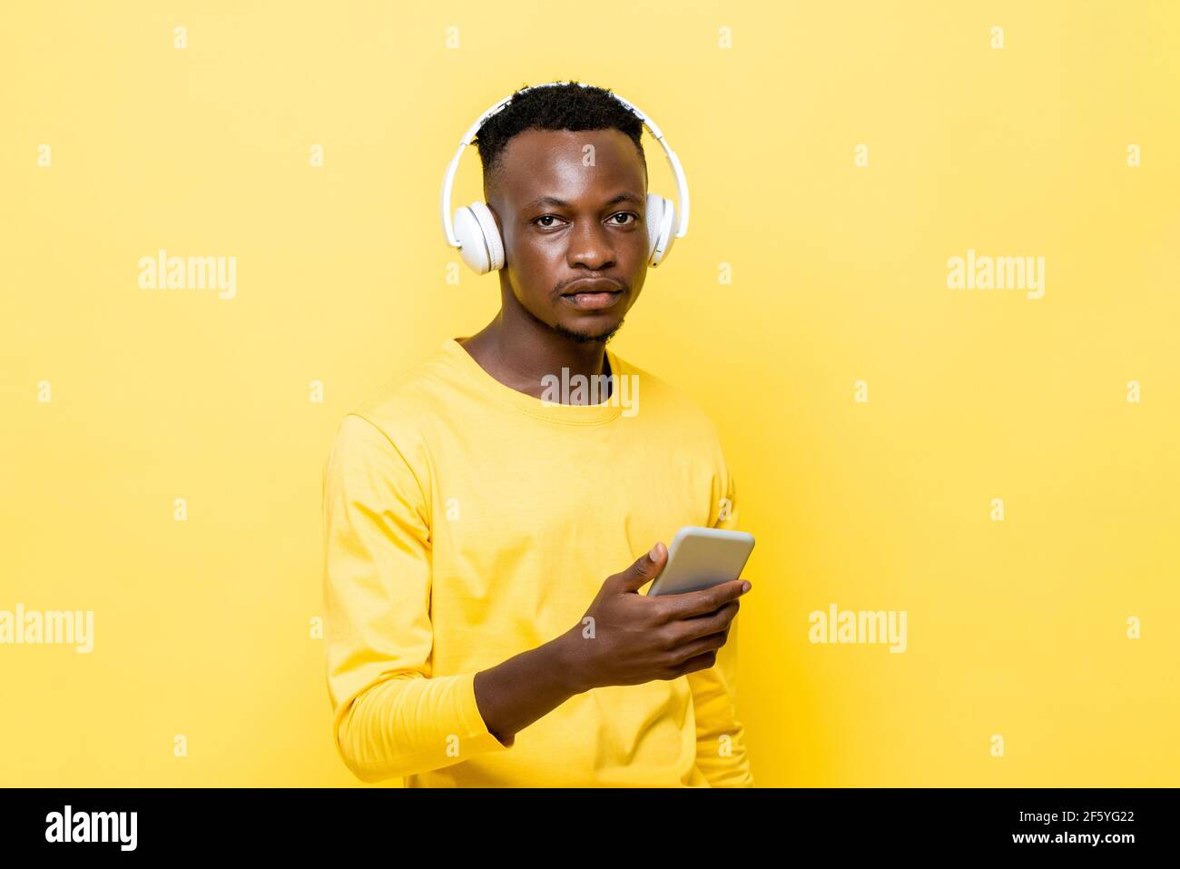 African man in casual attire wearing wireless headphones listening to ...