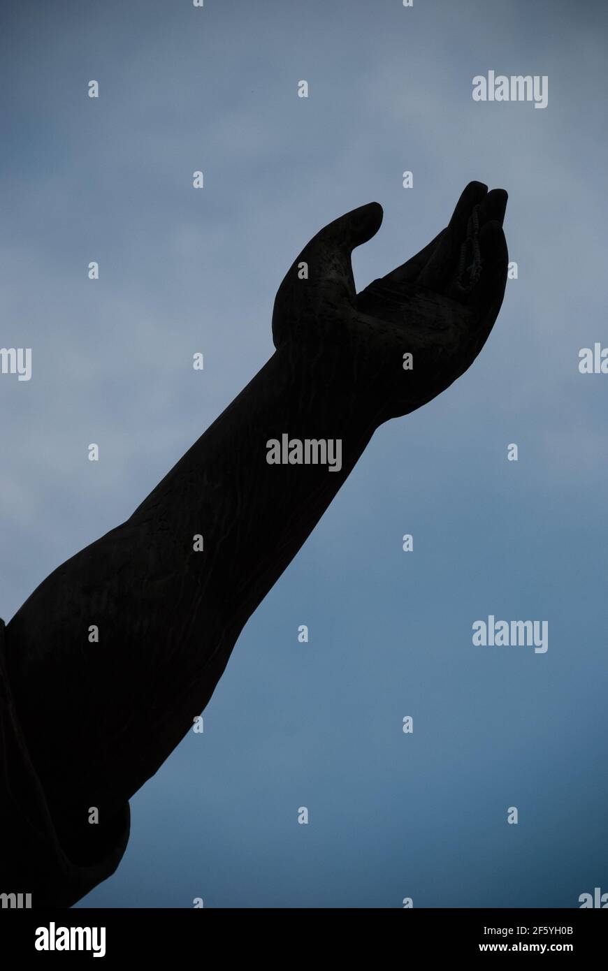 Silhouette of the arm of a statue against a dark blue sky Stock Photo ...