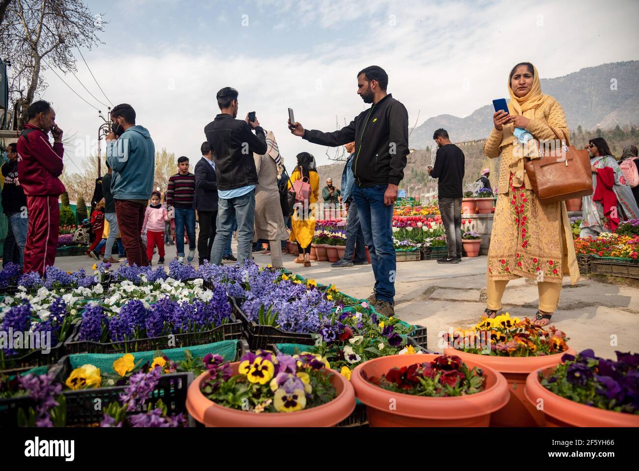 Srinagar, India. 28th Mar, 2021. People take photos next to flowers ...