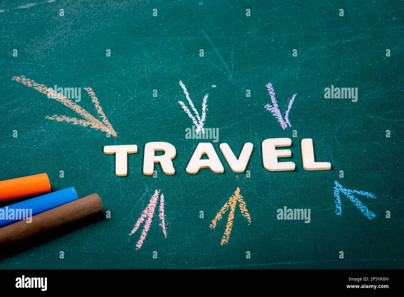 TRAVEL. White letters of the wooden alphabet. Colored pieces of chalk ...