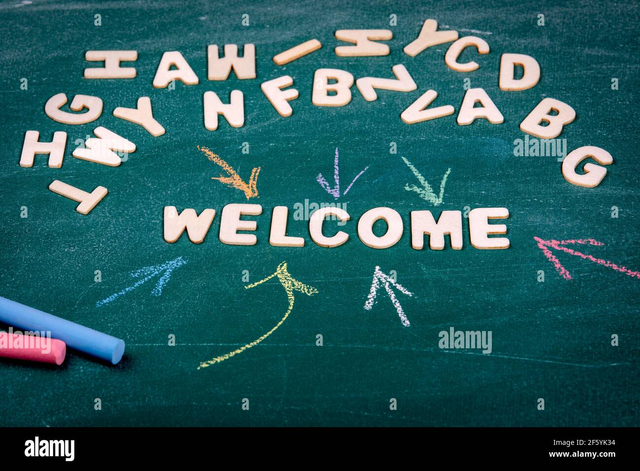 WELCOME. White letters of the wooden alphabet. Colored pieces of chalk ...