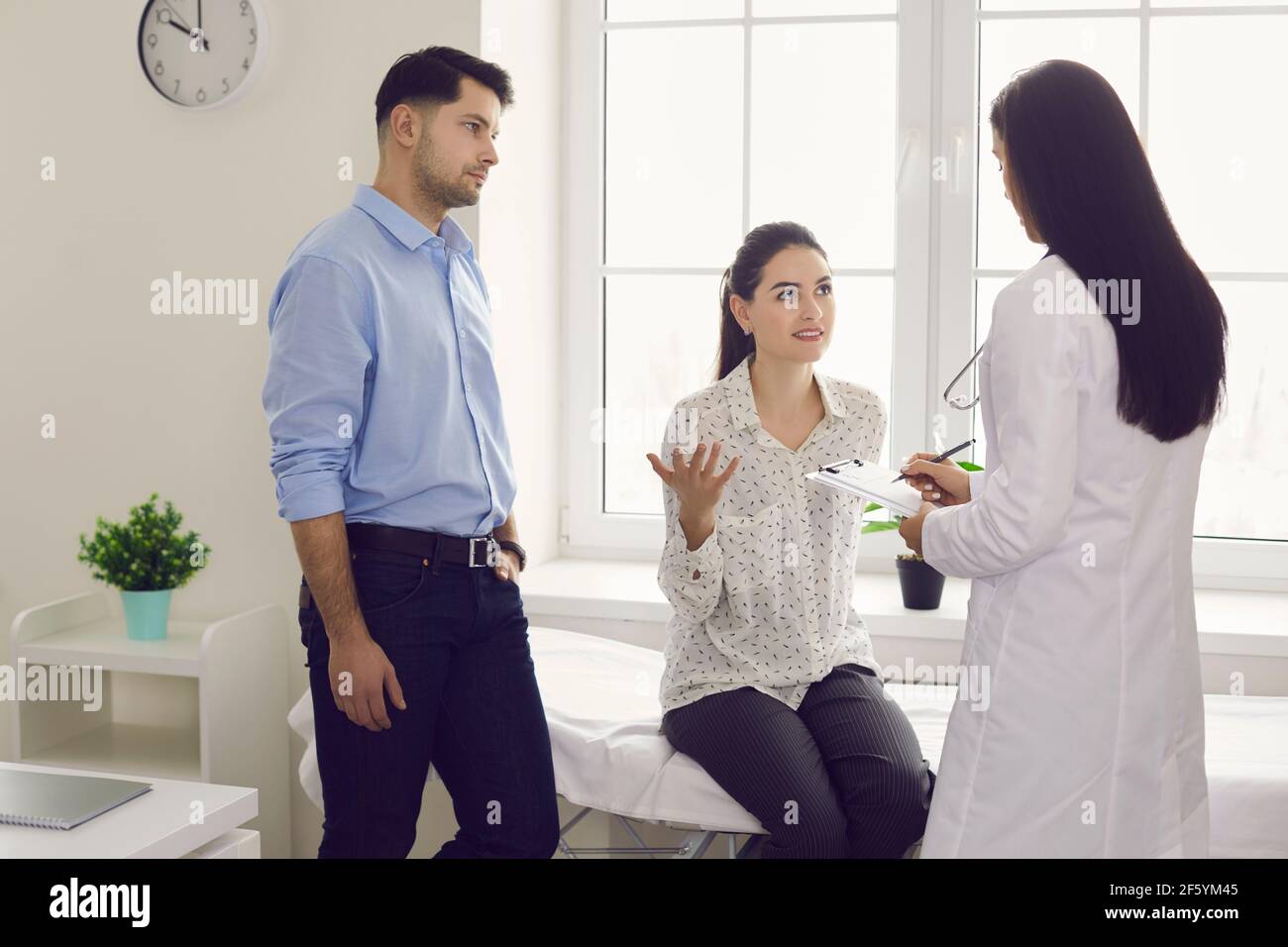 Worried woman and her husband tell a female doctor at a fertility ...
