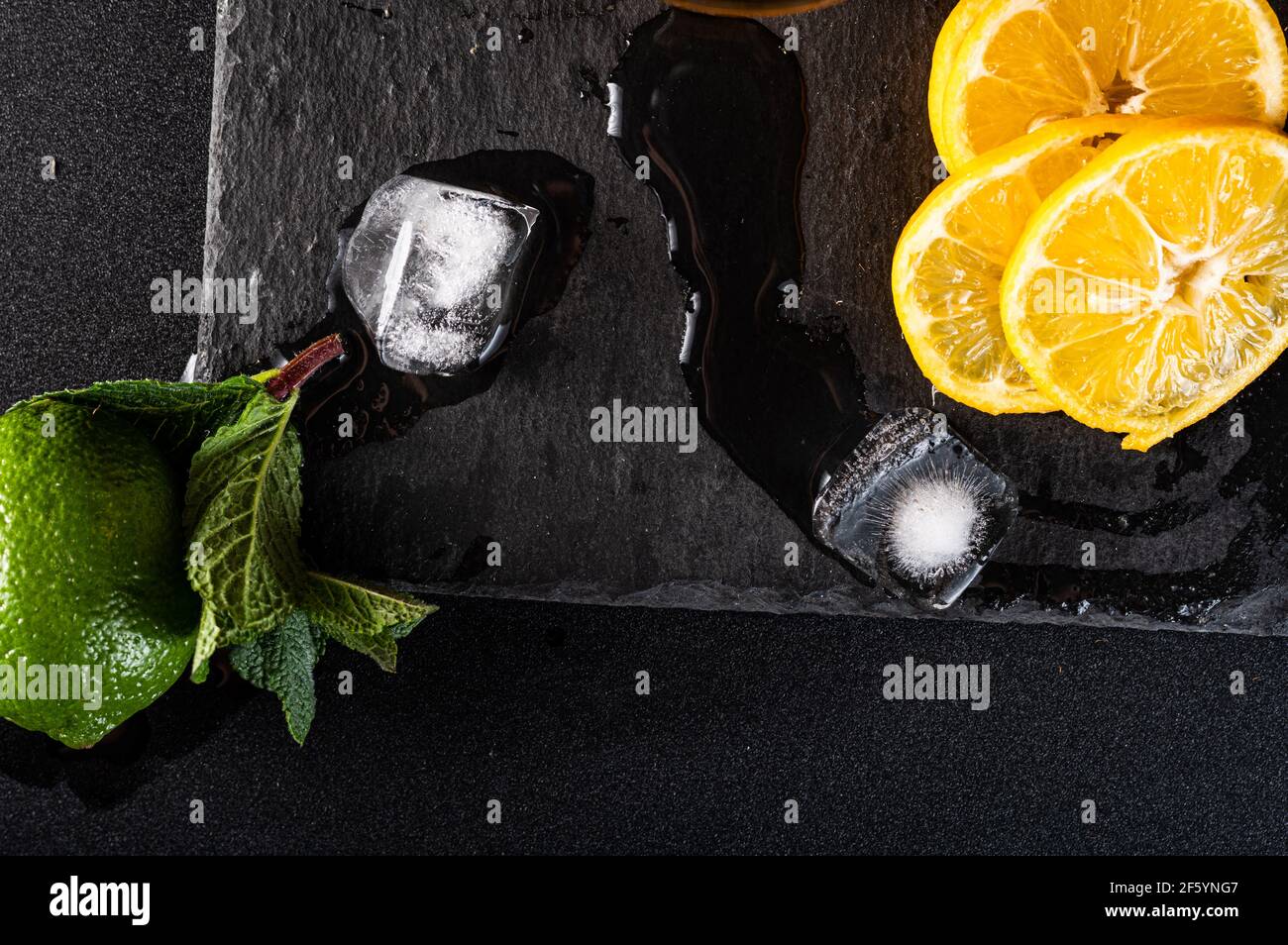 Natural ice cubes, lemon and mint. Melted ice cubes on a black ...