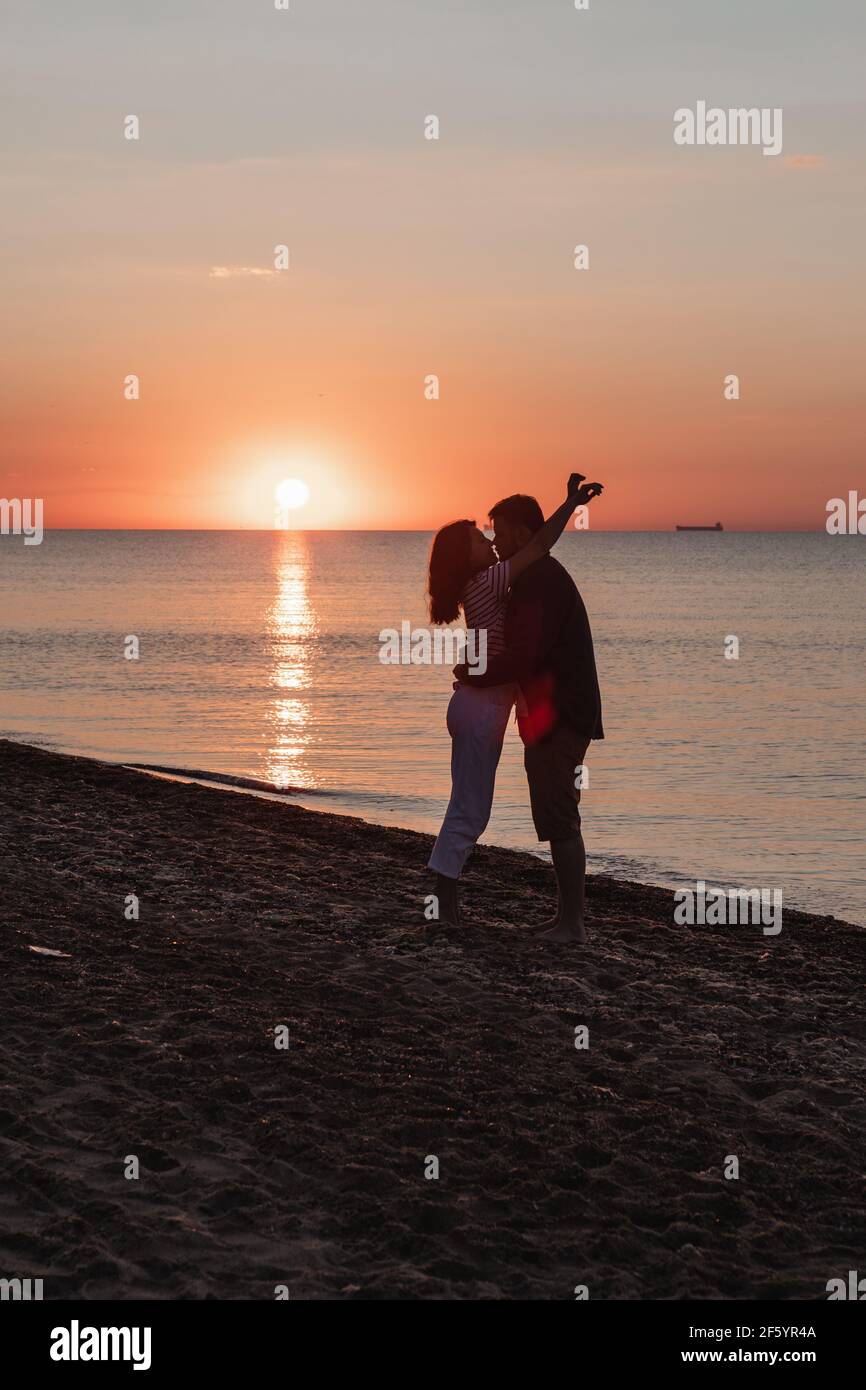 couple hugging look at sunset above sandy sea Stock Photo - Alamy