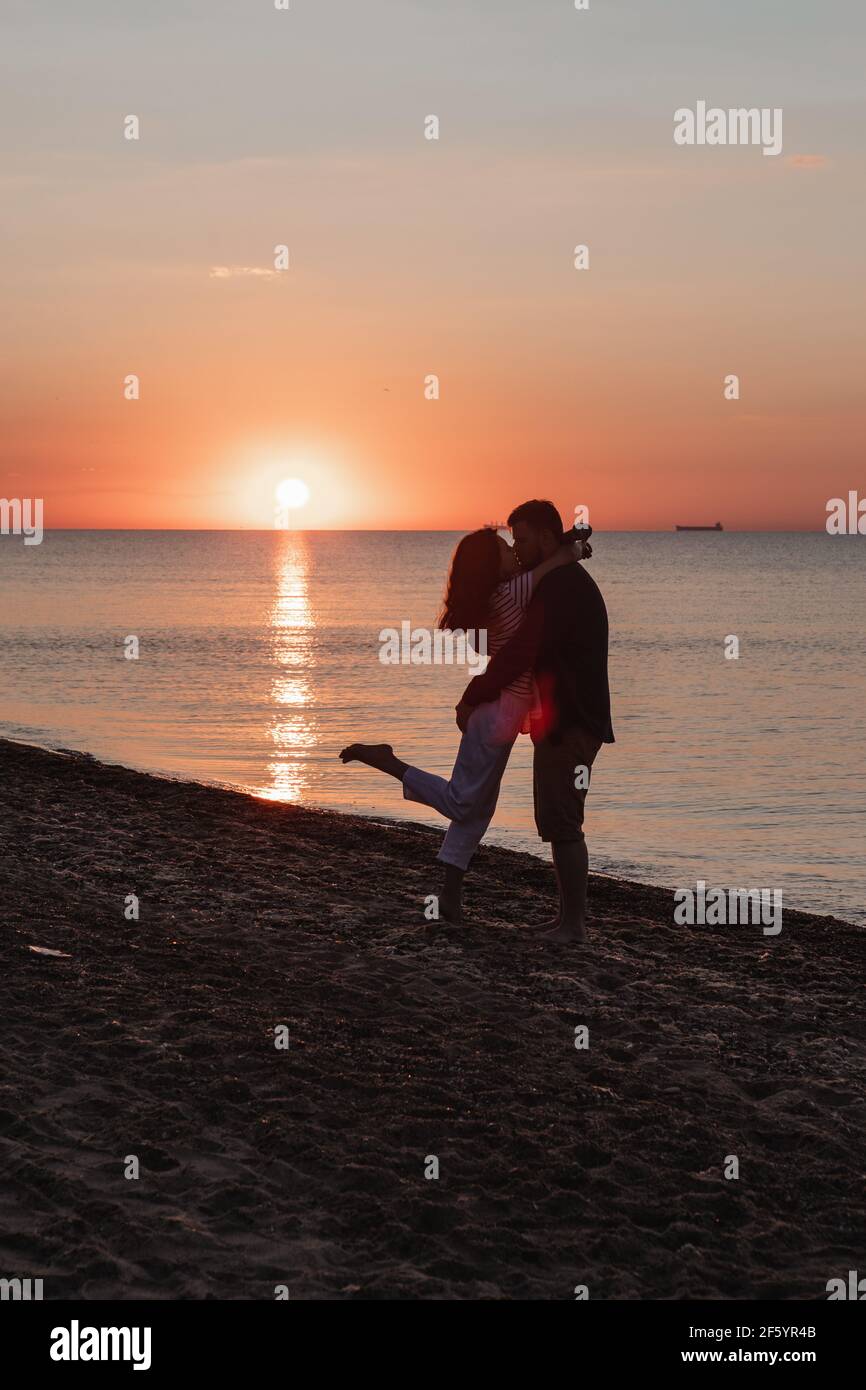 couple hugging look at sunset above sandy sea Stock Photo - Alamy