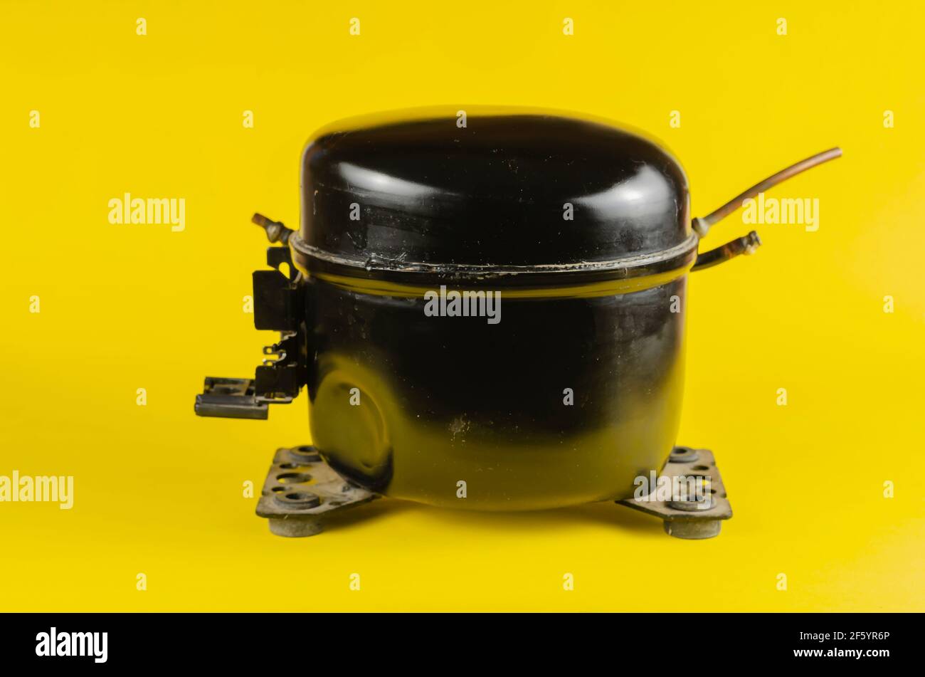Black refrigerator motor-compressor on yellow background. Old hermetic ...