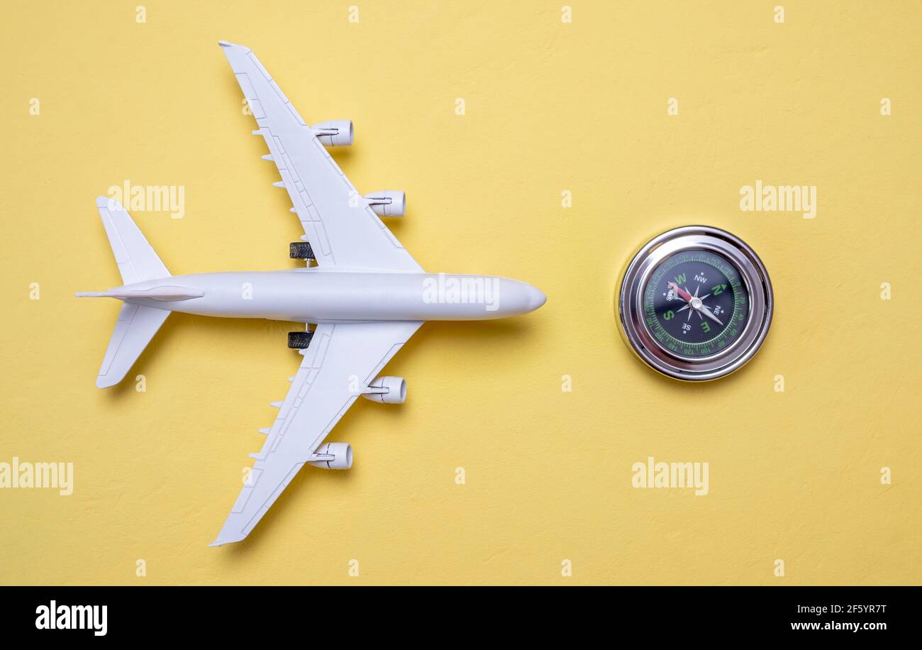 Miniature airplane and compass on a yellow background, top view ...