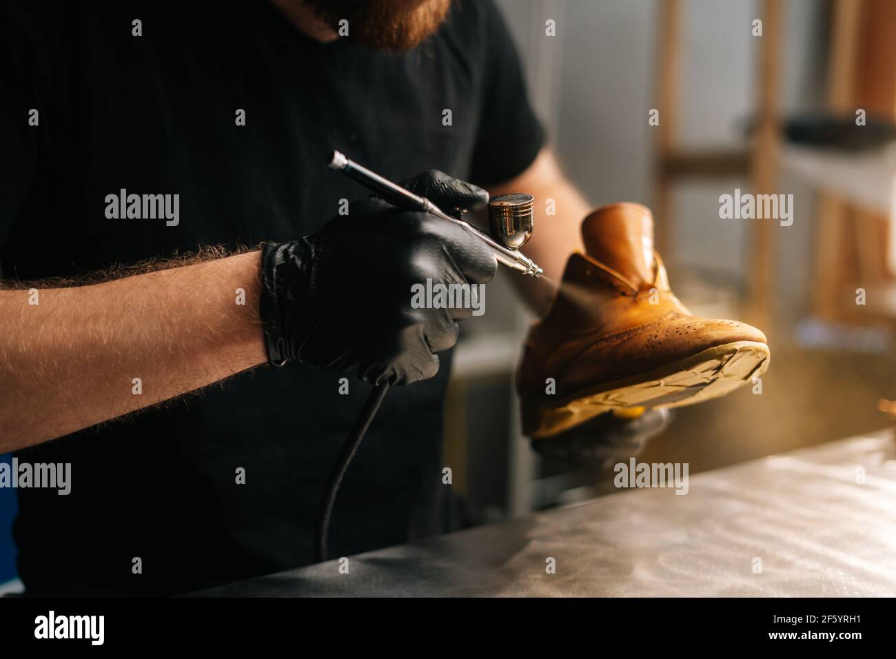 Close-up hands of unrecognizable shoemaker wearing black gloves ...
