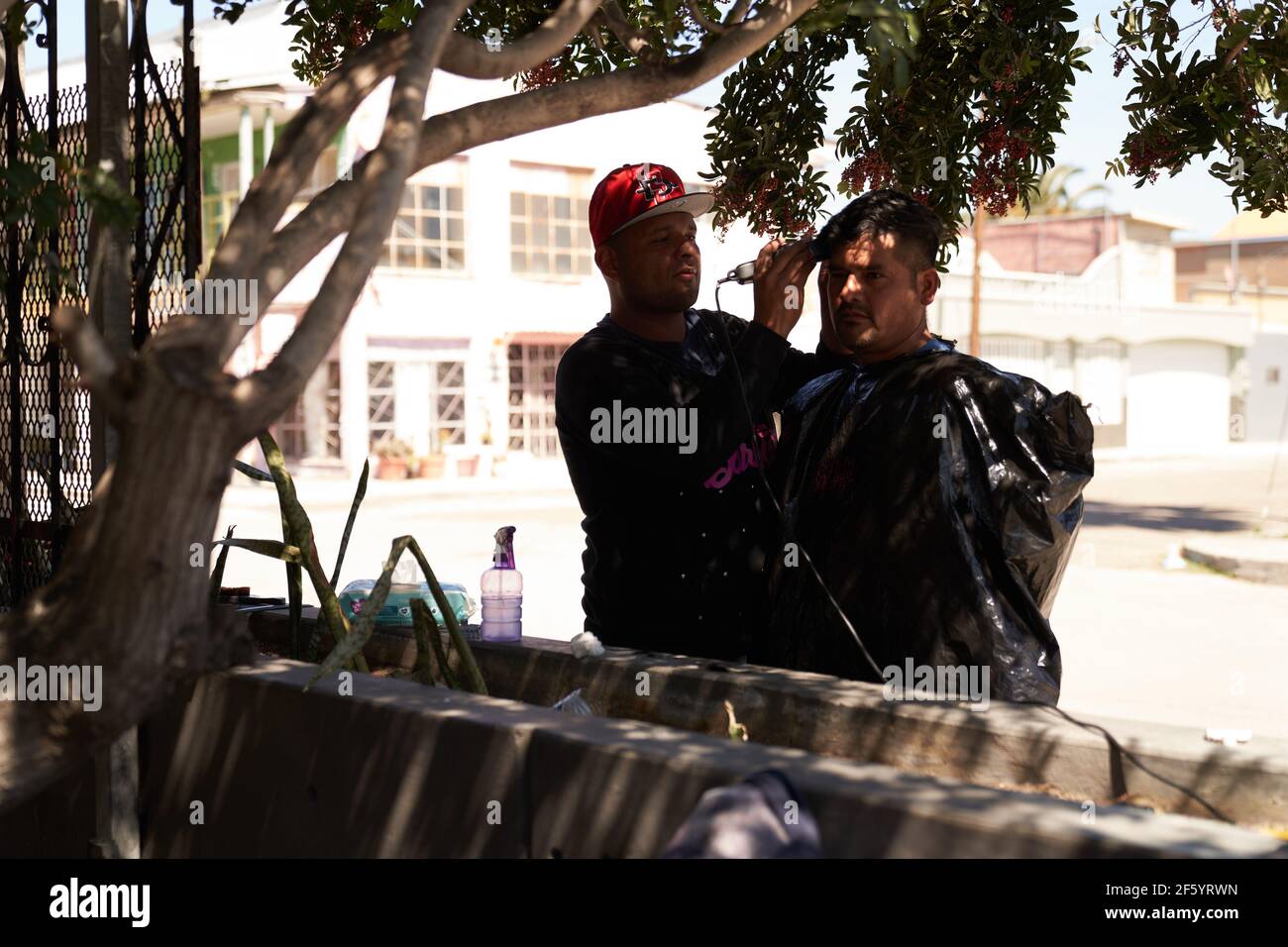 Tijuana, Mexico. 28th Mar, 2021. A migrant man gives another man a ...