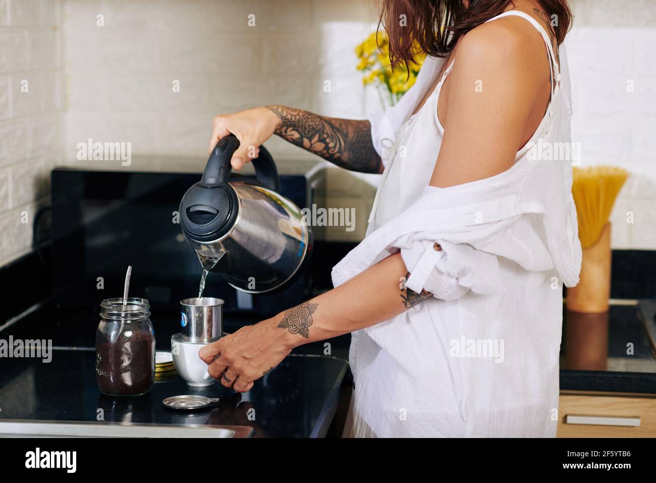 Cropped image of young woman hot water in Vietnamese phin filter at her ...