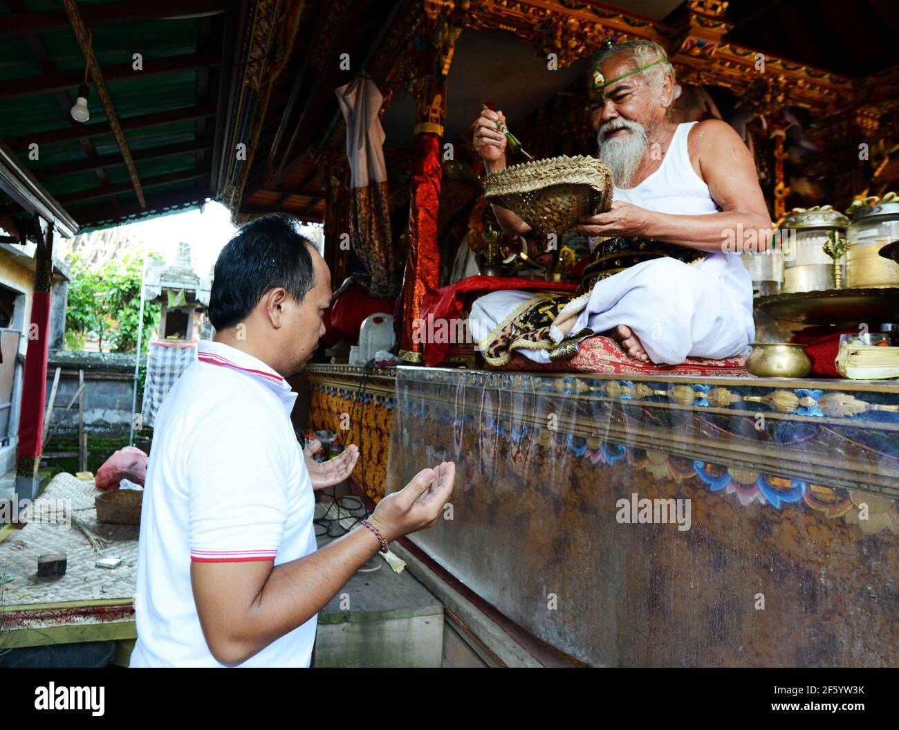 A Balinese Hindu priest blessing a groom in a pre wedding ceremony in a ...
