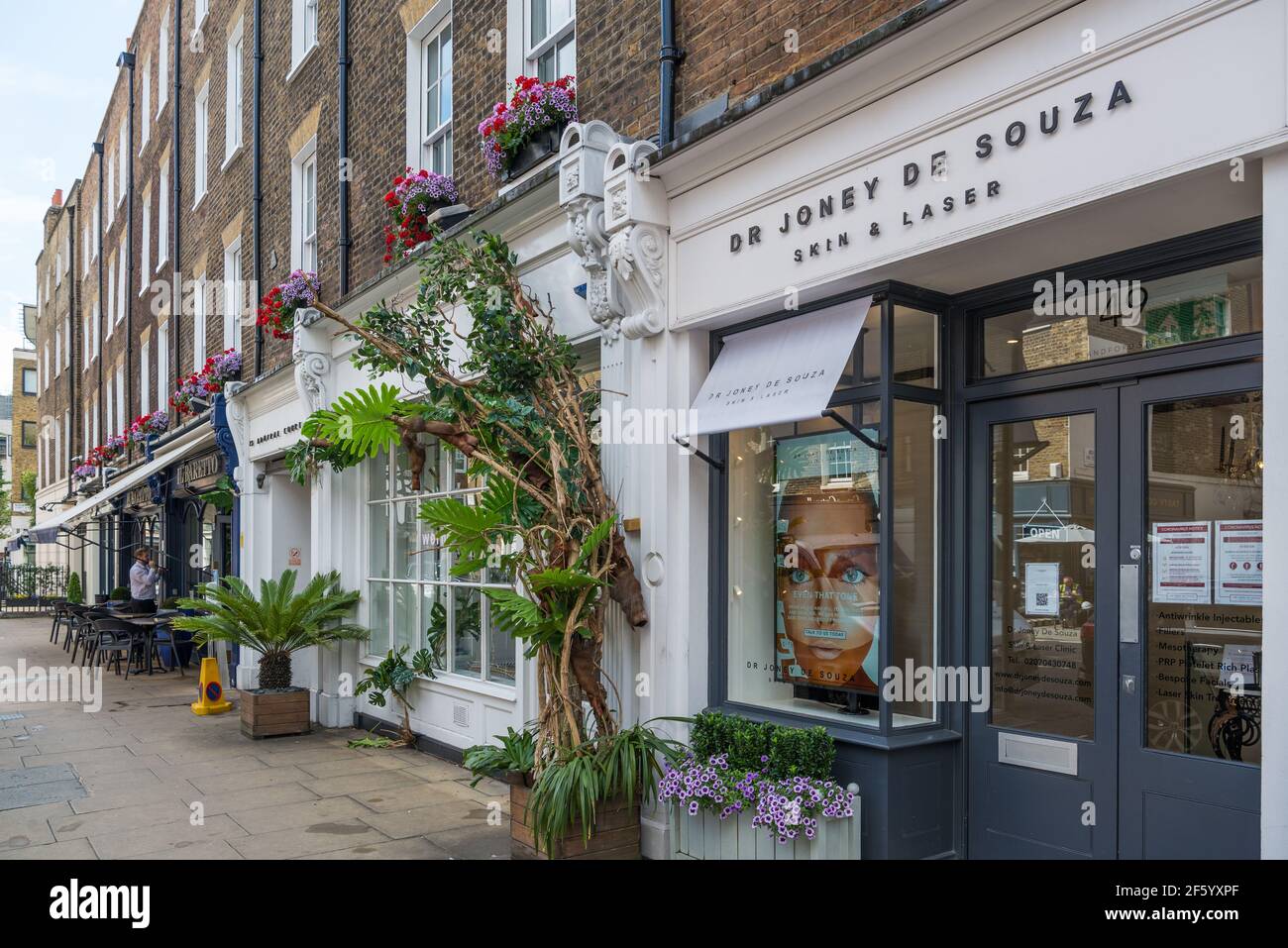 View of shopfronts with colourful window box flower displays in ...