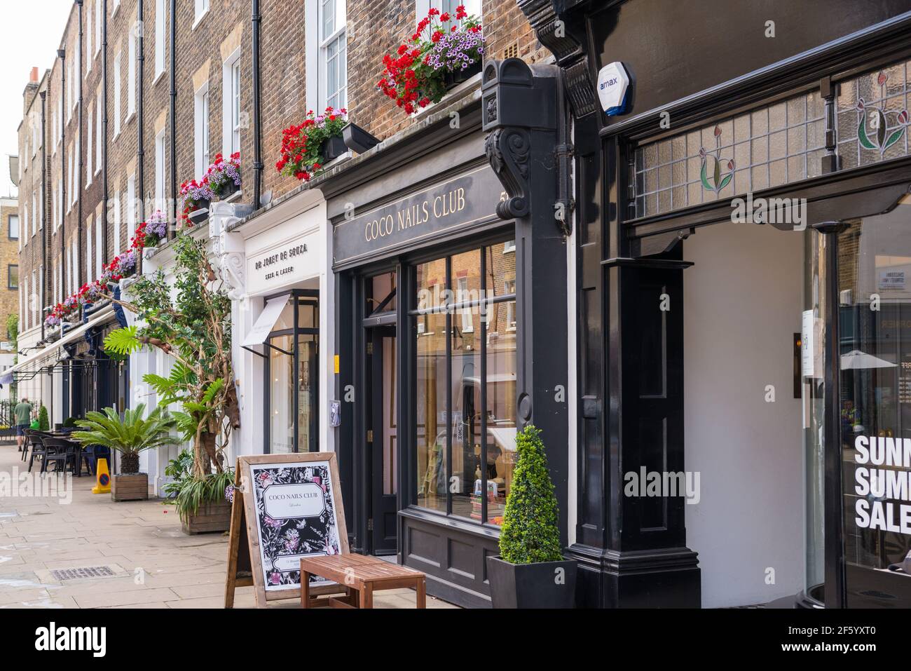 View of shopfronts with colourful window box flower displays in ...
