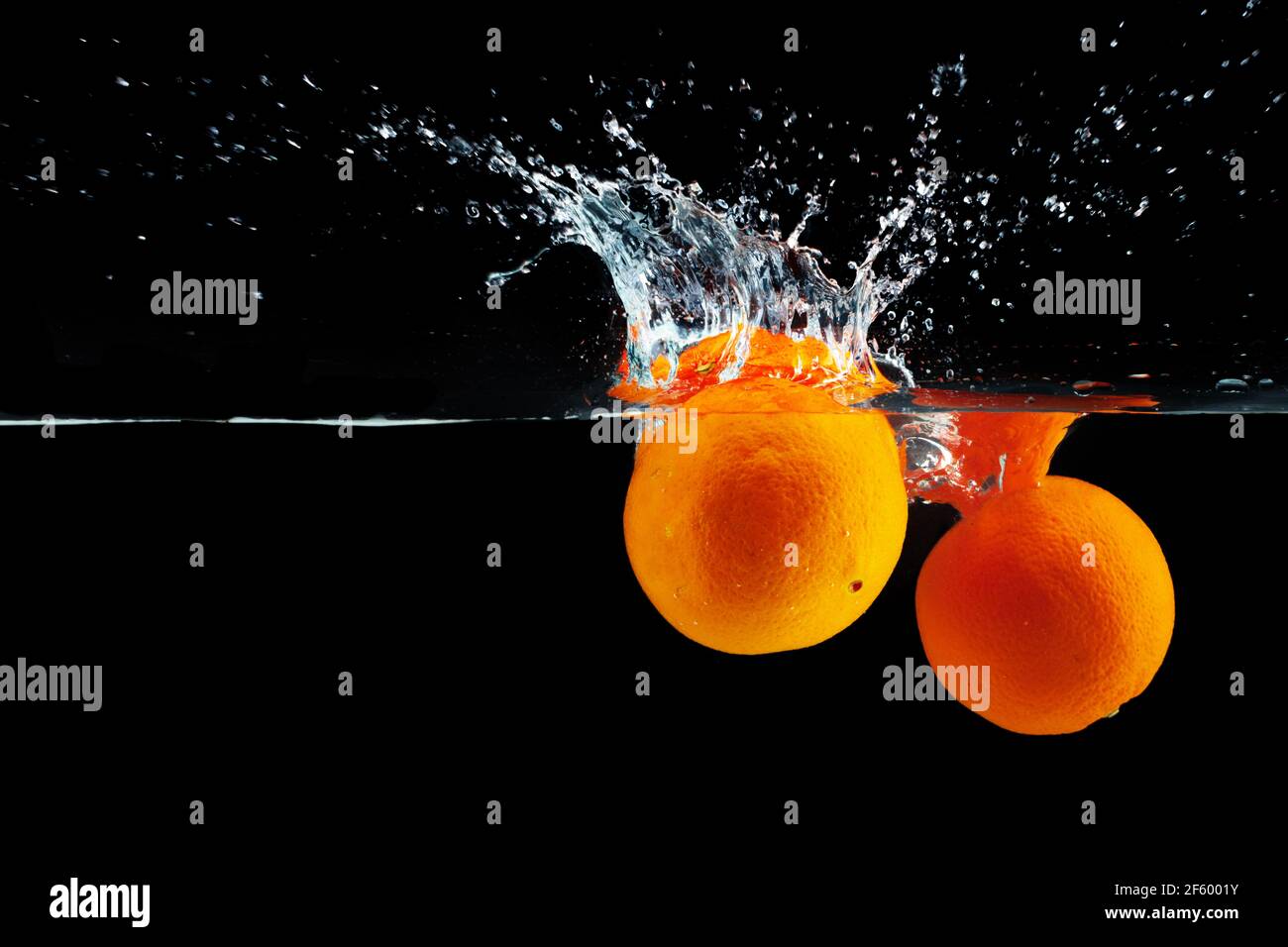 Oranges falling into water against black background, studio shot Stock ...