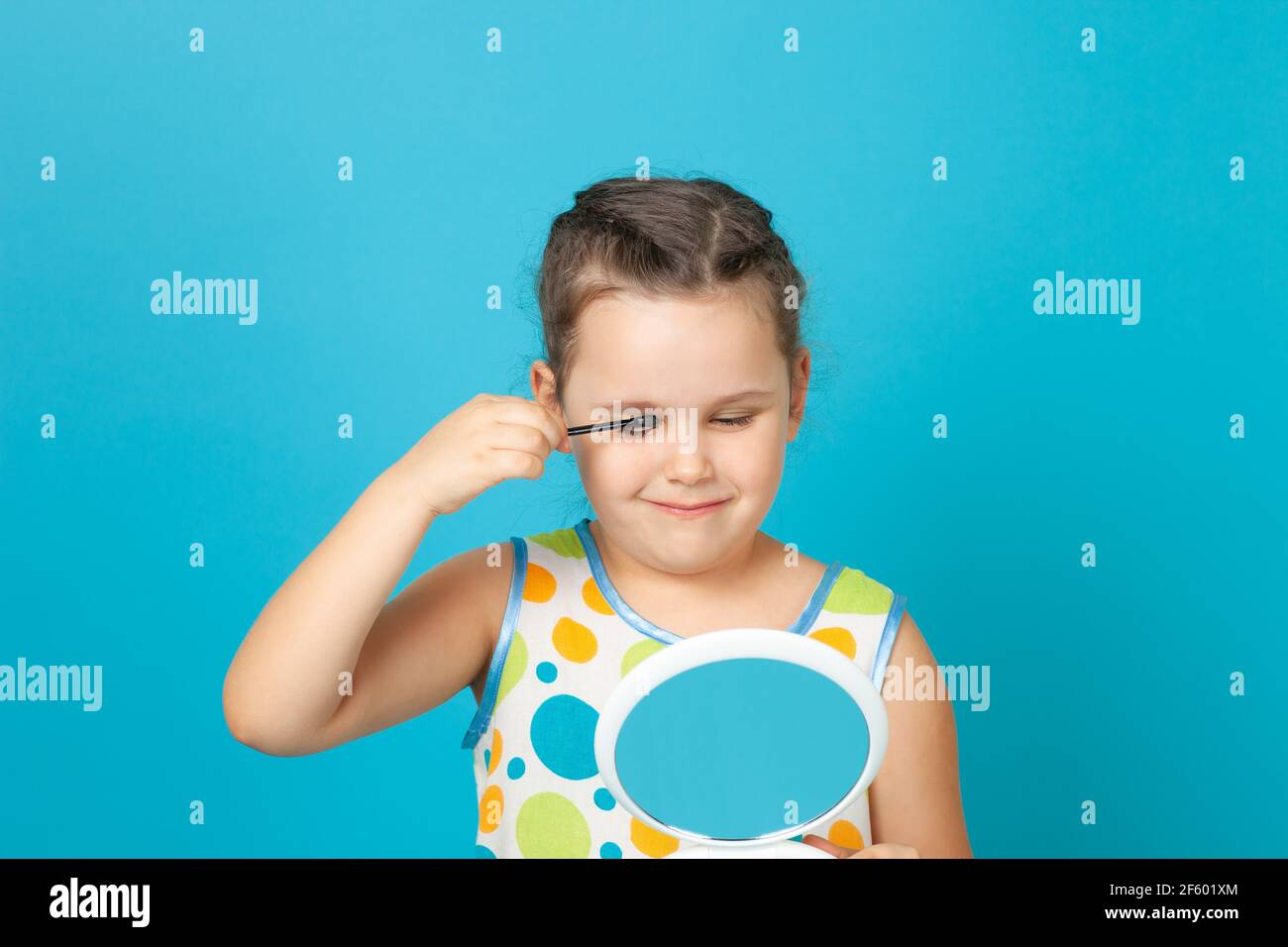 a five-year-old girl puts green shiny eye shadow on her eyelids and ...