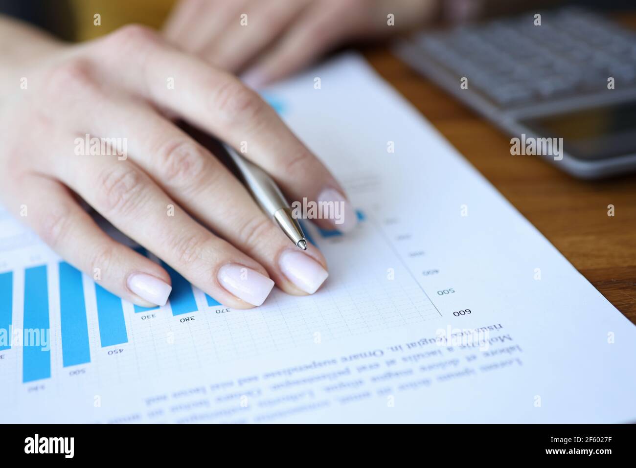 Female hand with ballpoint pen lying on document with graph closeup ...