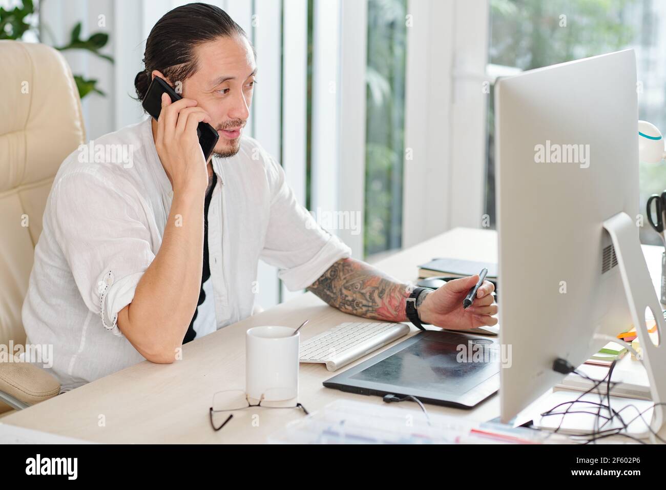 Handsome professional graphic designer talking on phone with client and ...