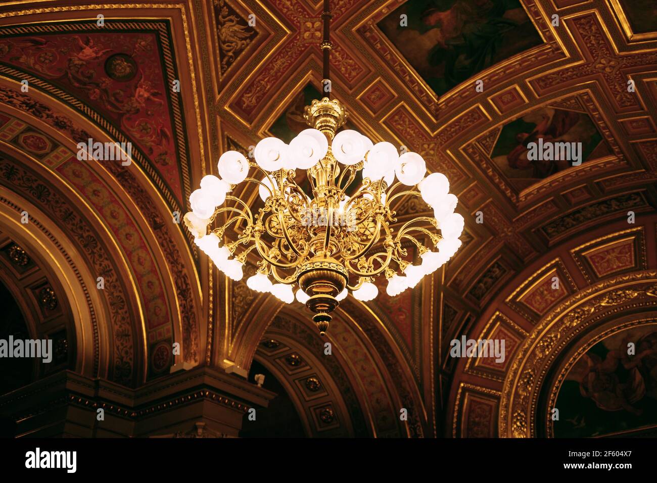 Luxurious interior chandelier with lit bulbs and a dark background. A ...