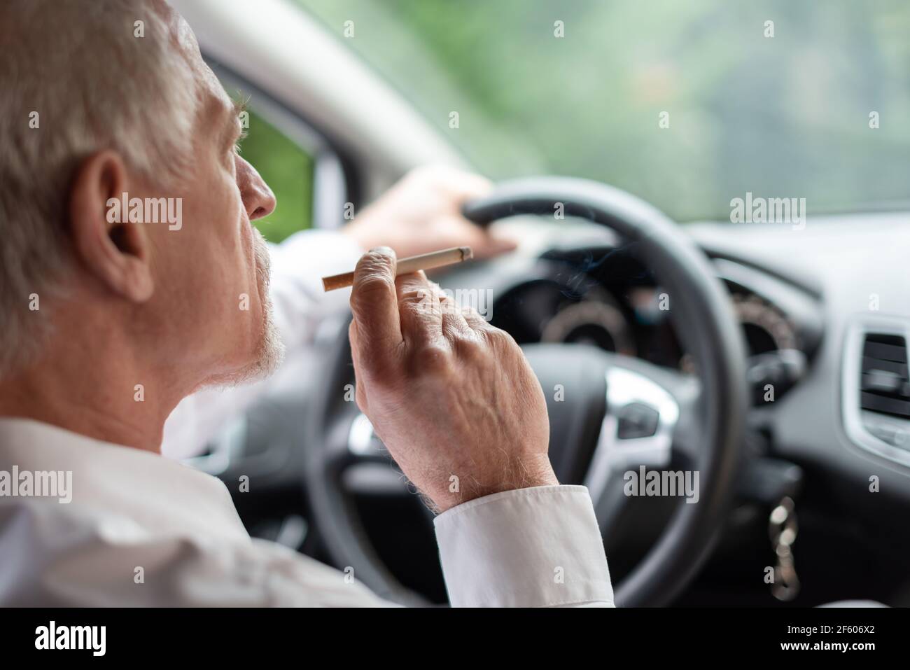 Senior man smoking a cigarette while driving Stock Photo - Alamy