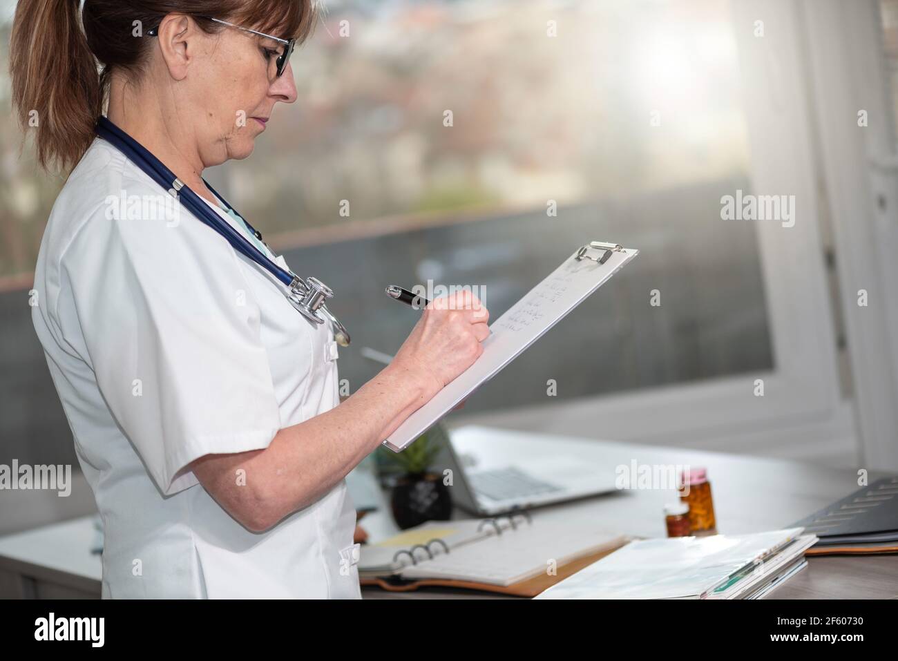 Female doctor standing and taking notes on clipboard hi-res stock ...
