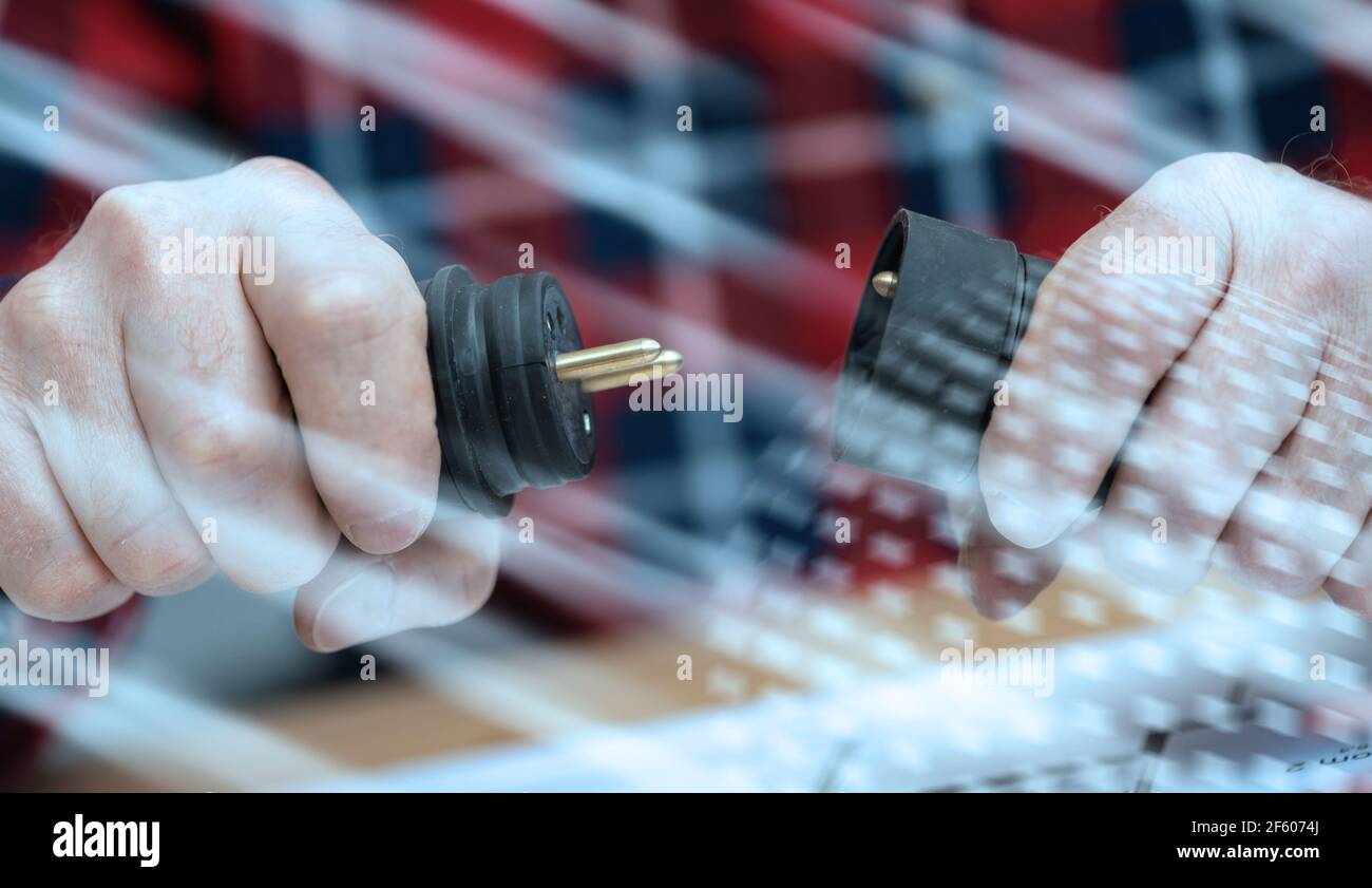 Electrician hands holding electrical plugs; light effect Stock Photo ...