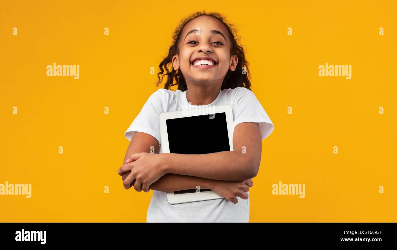 Technology Lover. Excited black girl hugging tablet Stock Photo - Alamy