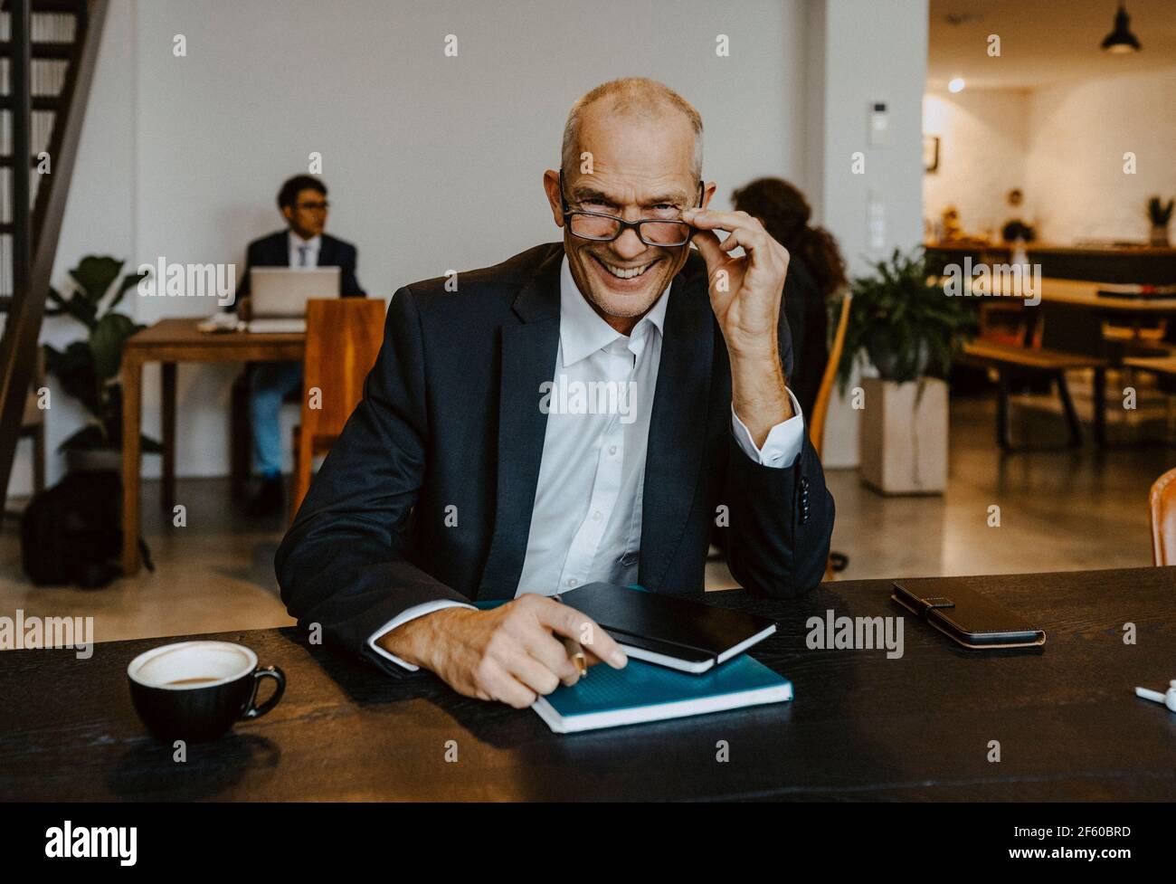Portrait of smiling male entrepreneur with eyes at conference table in ...
