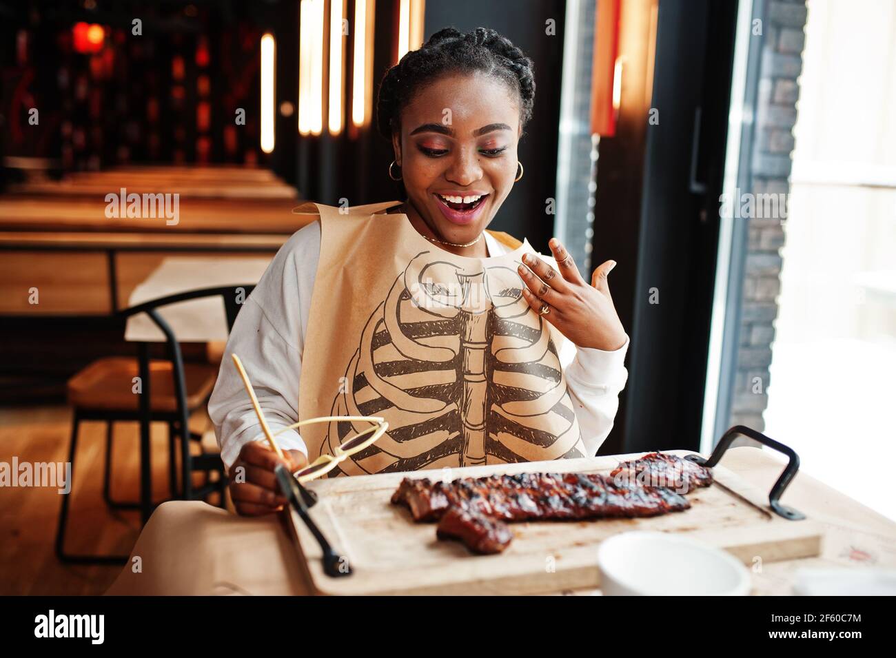 African woman eat spicy hot grilled spare ribs on wooden desk Stock ...