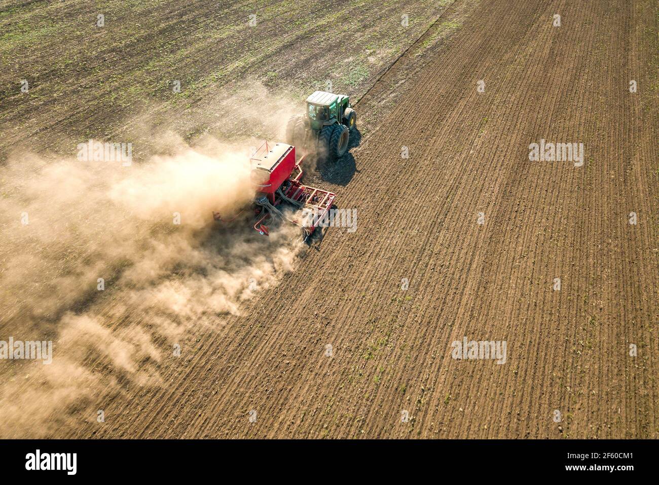 Top down aerial view of green tractor cultivating ground and seeding a ...