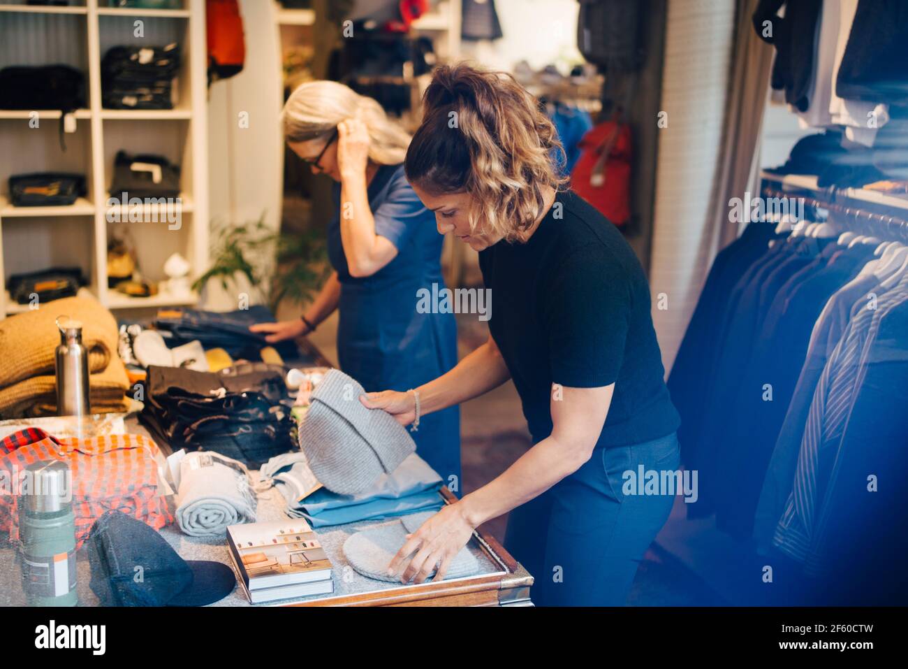 Female coworkers arranging clothes in retail store Stock Photo - Alamy