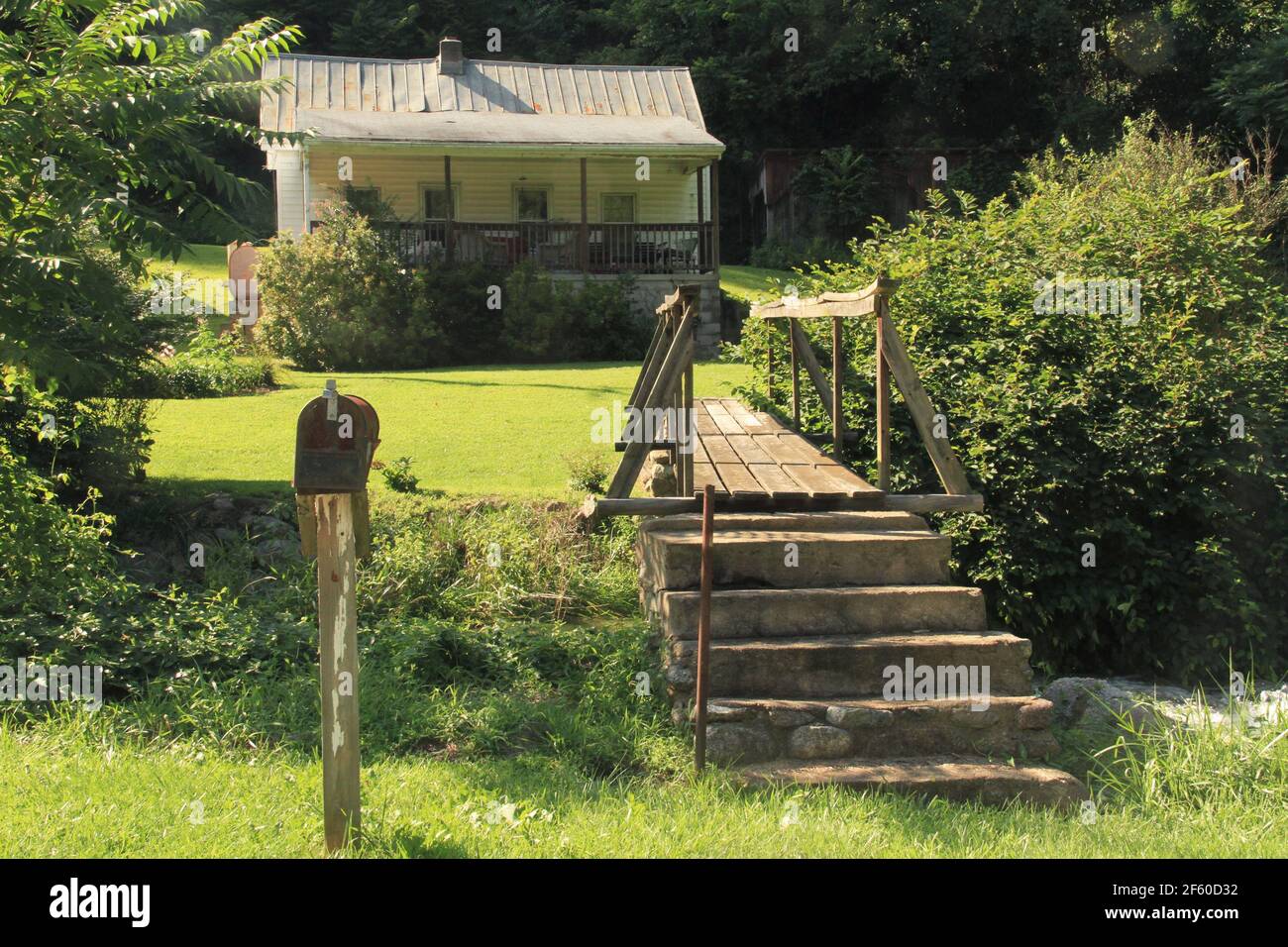 Small hand-made wooden bridge crossing over a stream in front of a ...