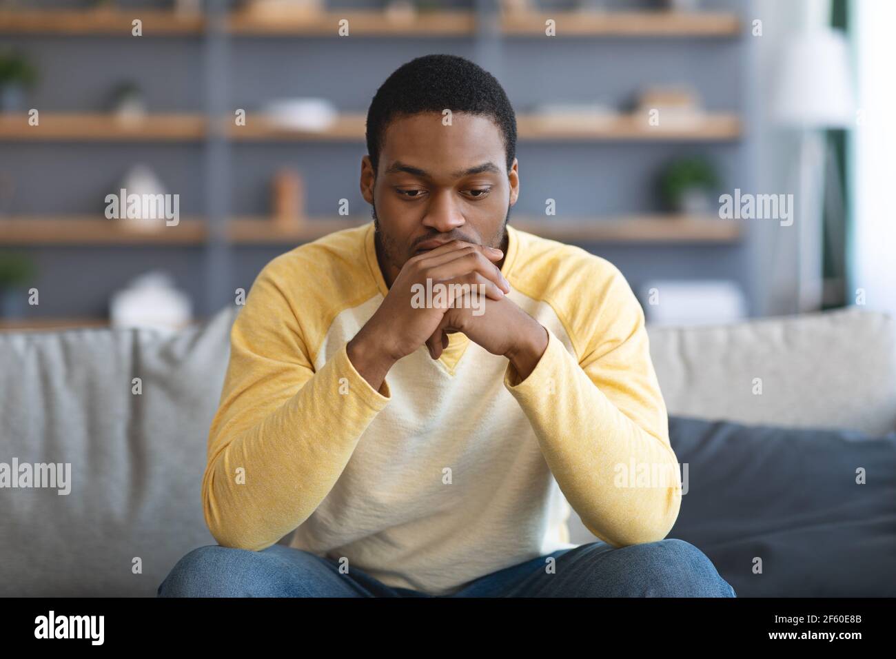 Upset black man having problems, sitting on couch at home Stock Photo ...