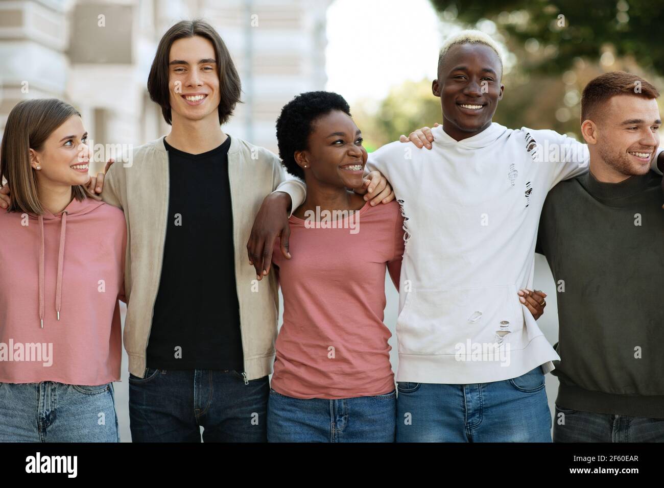International group of students hugging while standing on the street ...